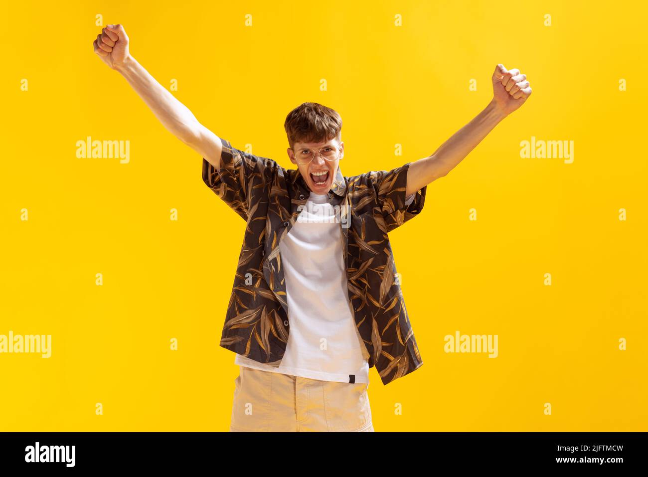 Young boy with surprised happy expression isolated over bright yellow ...