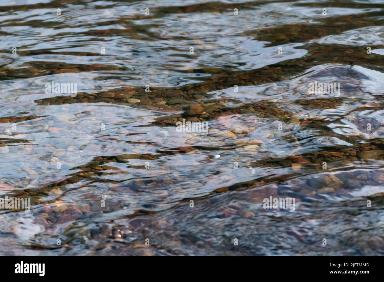 Clean transparent creek flows over gravel close up, ripple wavy water ...