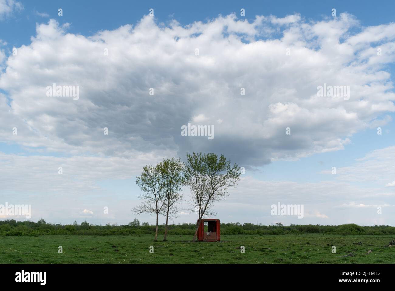 Unusual round cloud forming above plain field, abandoned newspaper shop ...