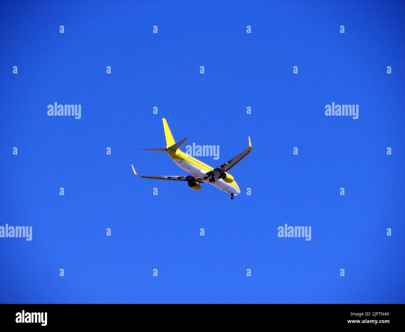 A plane in the blue sky flies high, carrying passengers Stock Photo - Alamy