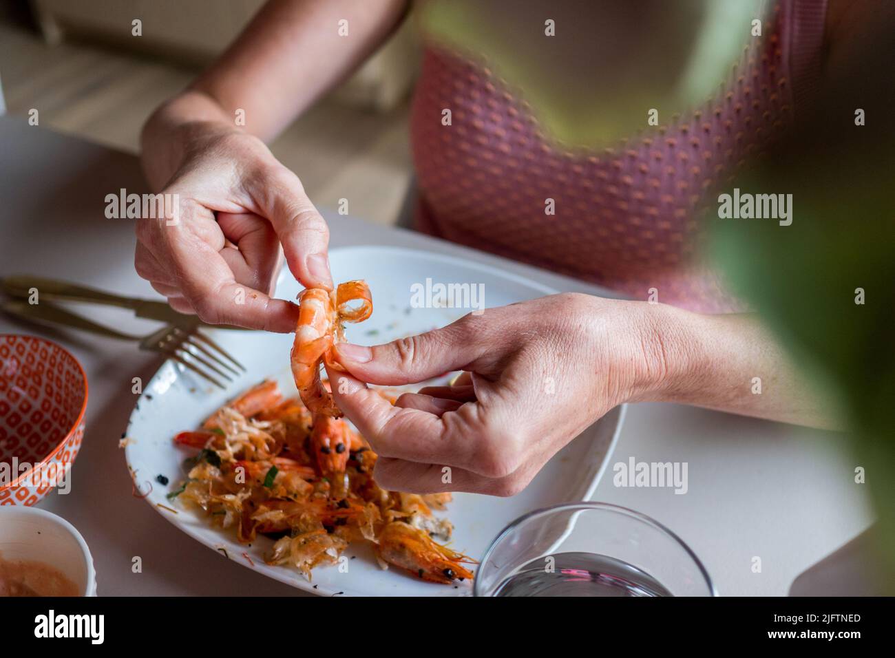 Woman eating and peeling prawns at home Stock Photo - Alamy
