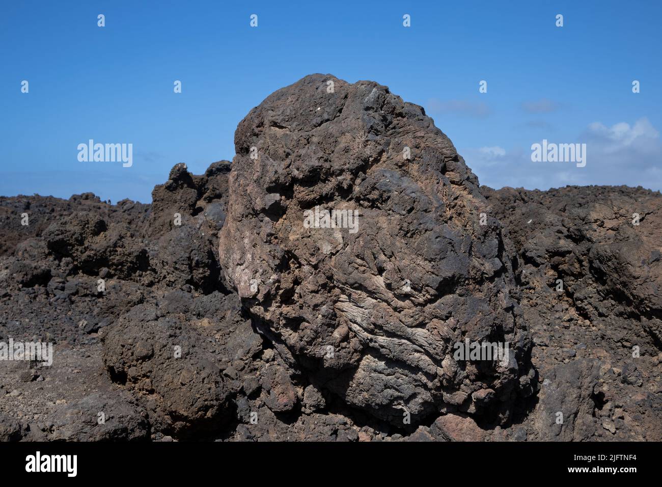 Big and many small volcanic rocks and stones, colored from dark brown ...