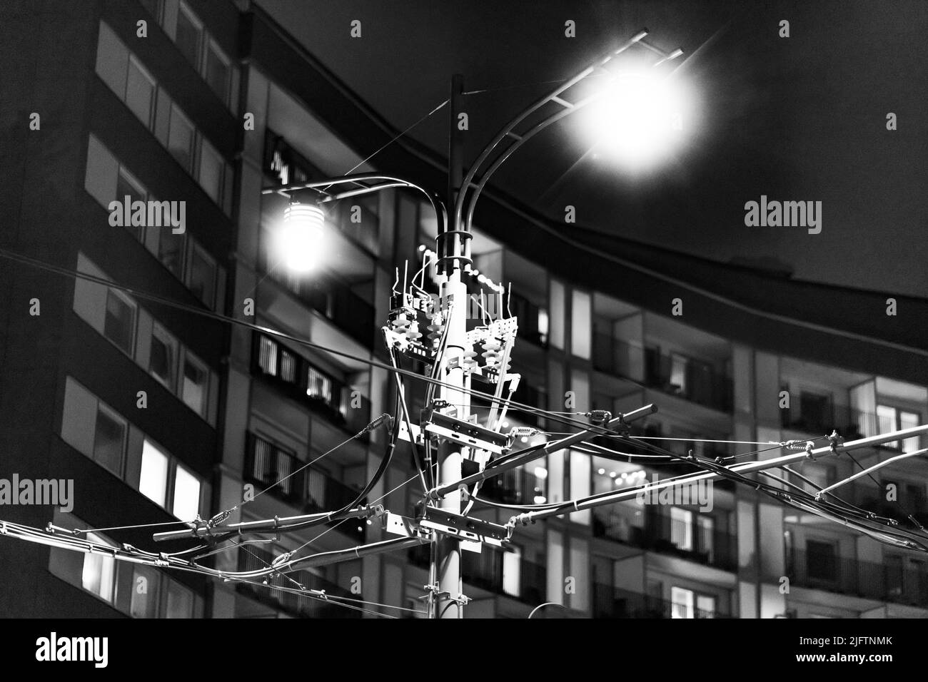 A low angle shot of two street lamps turned on at night in grayscale ...