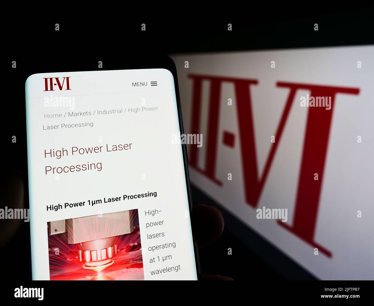 Person holding cellphone with webpage of US semiconductor company II-VI ...