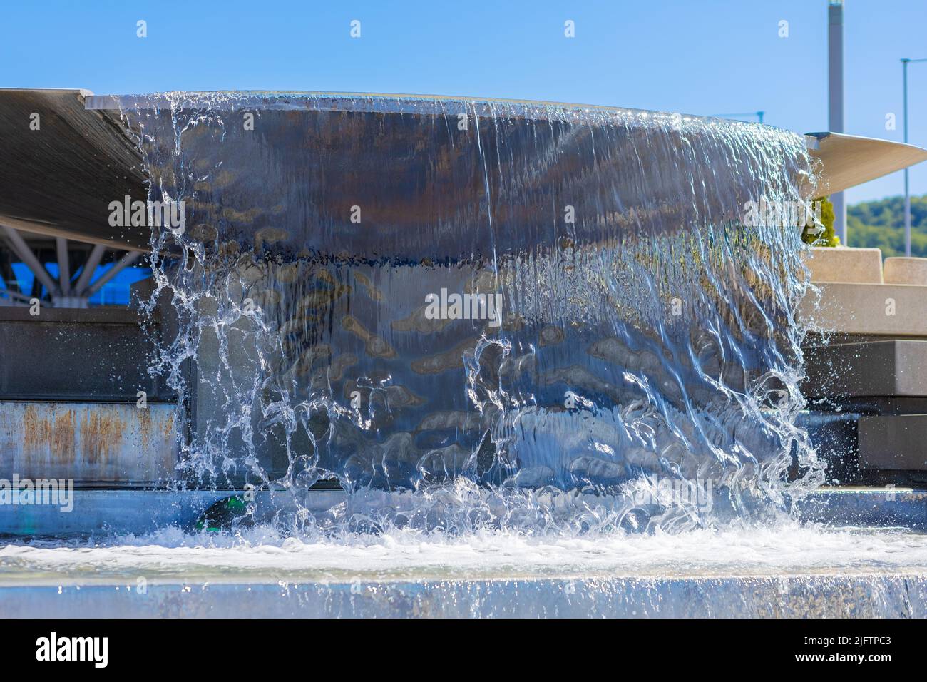 A stream of clear water pouring from large bowl. Cascading street ...