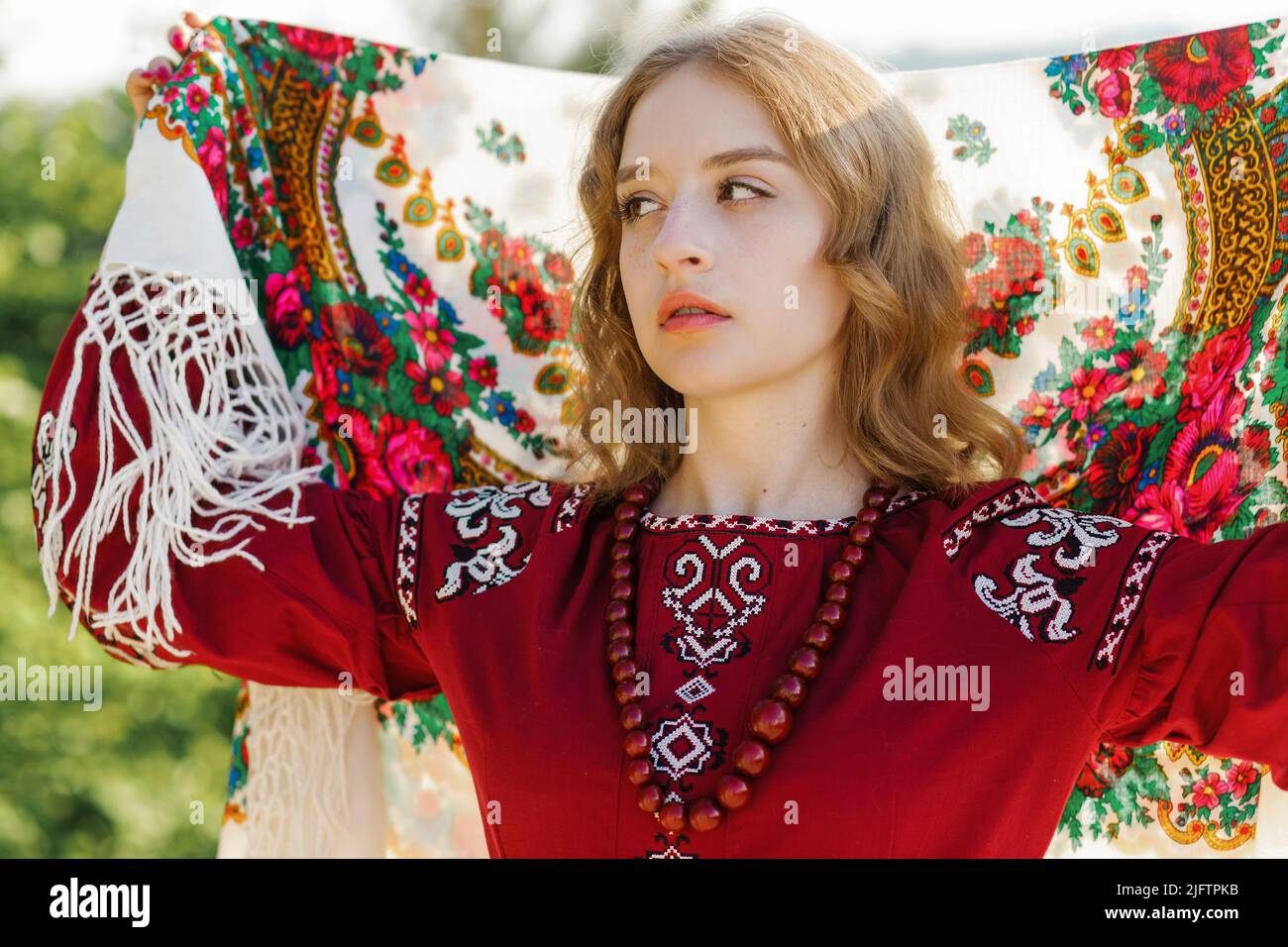 Portrait of a serious blonde in traditional national clothes posing ...