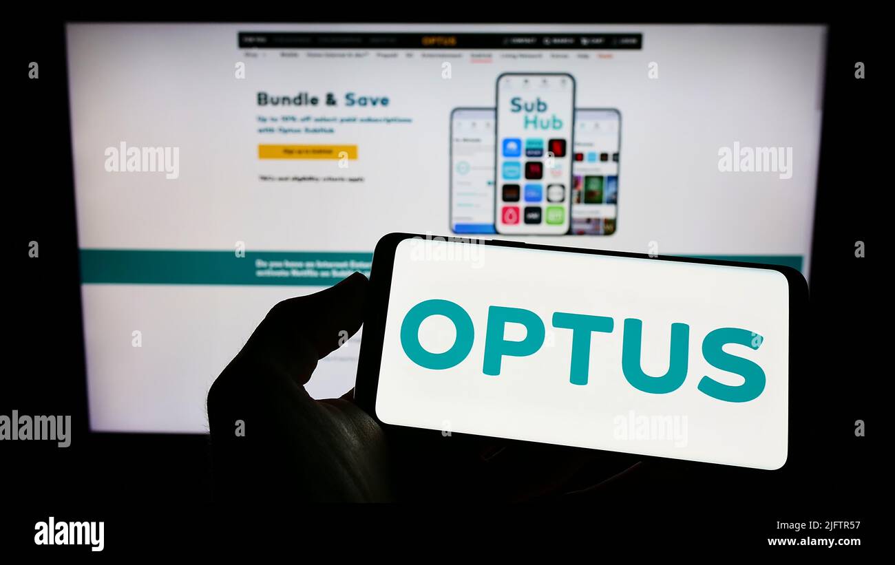 Person holding cellphone with logo of communications company SingTel Optus Pty. Ltd. on screen ...