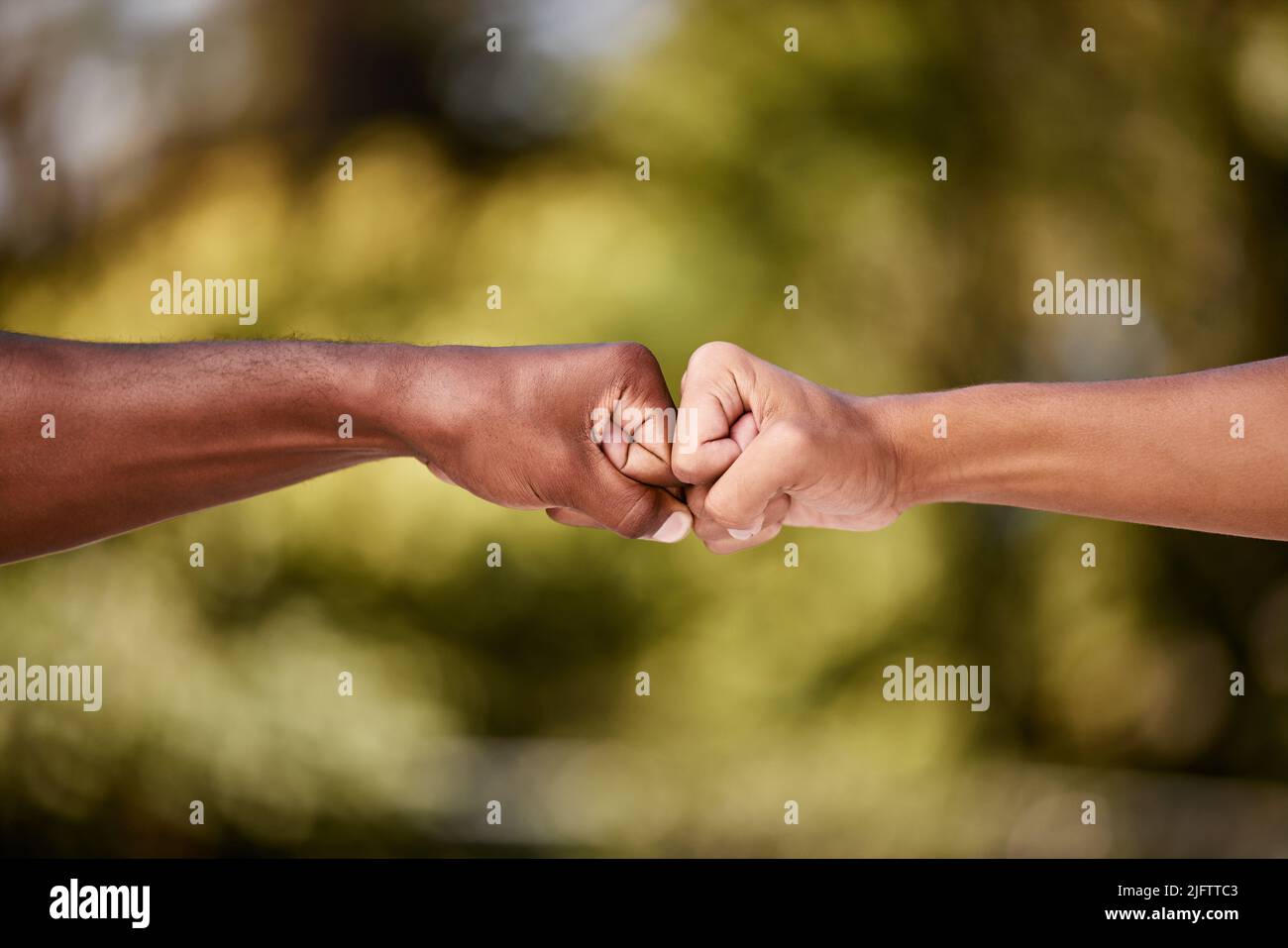 Fist bump of two interracial men outdoor against a blur background ...
