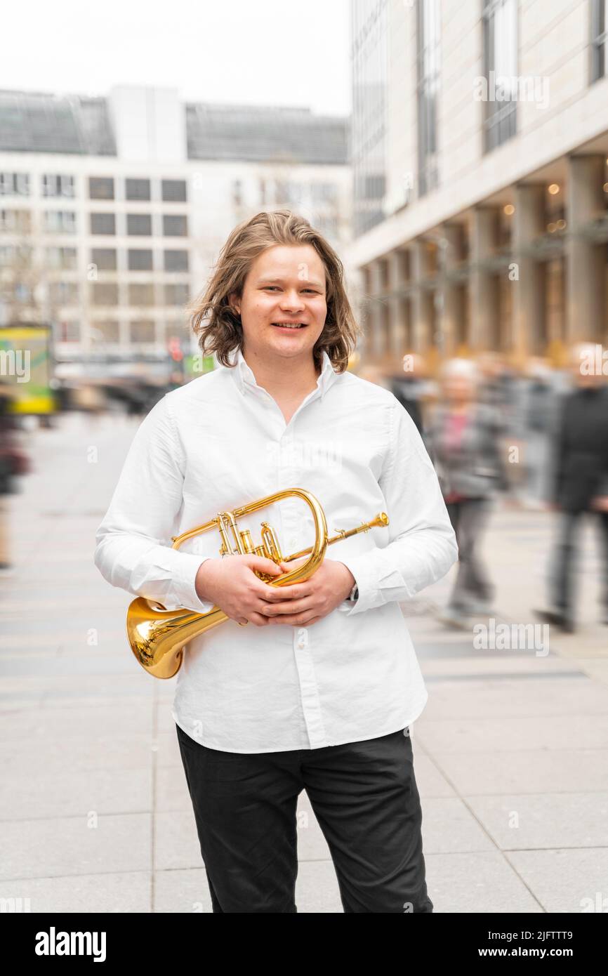Young caucasian long-haired blond well-dressed man posing with golden ...