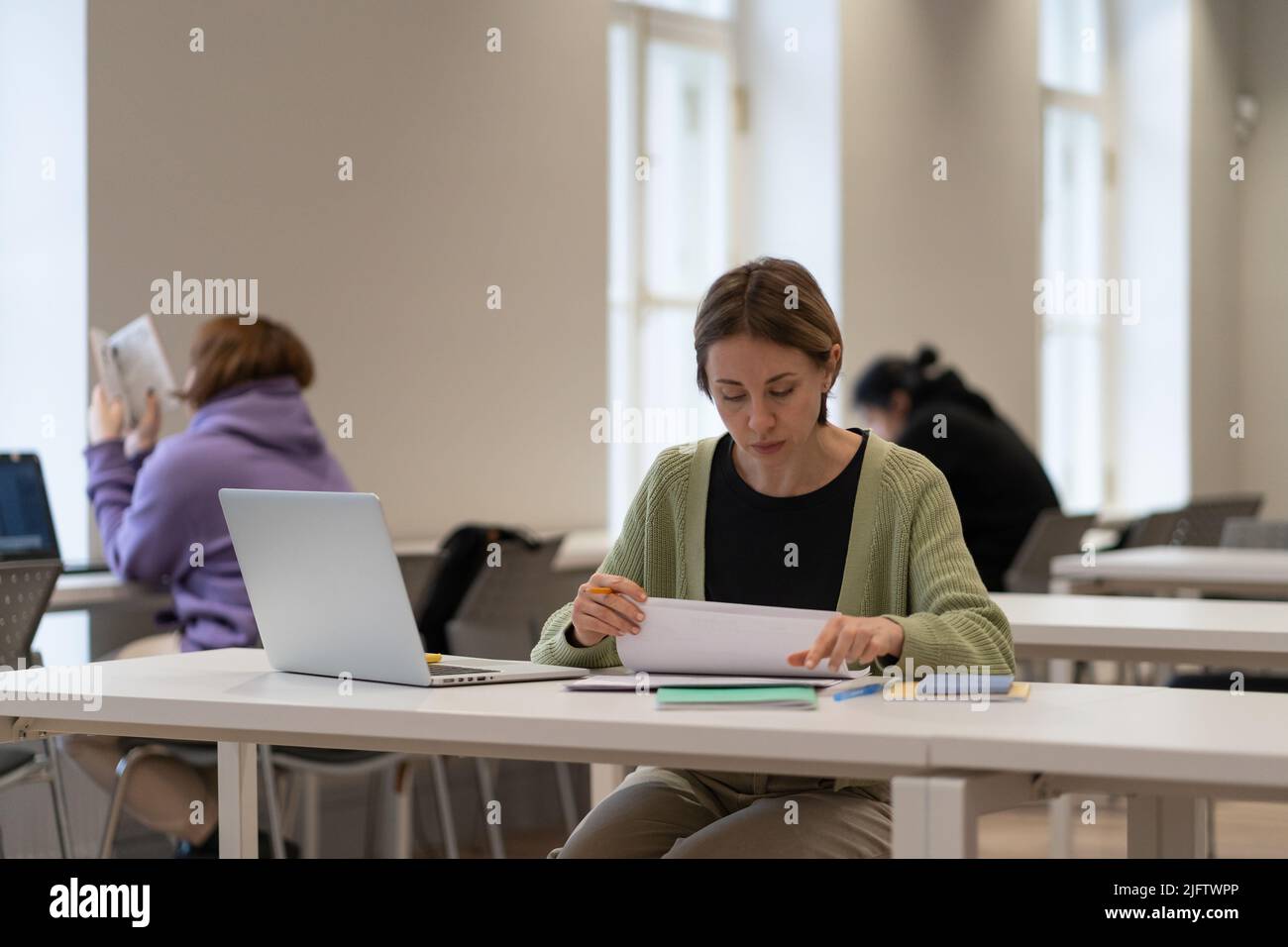 Hard-working female mature student reading architectural drawings while ...