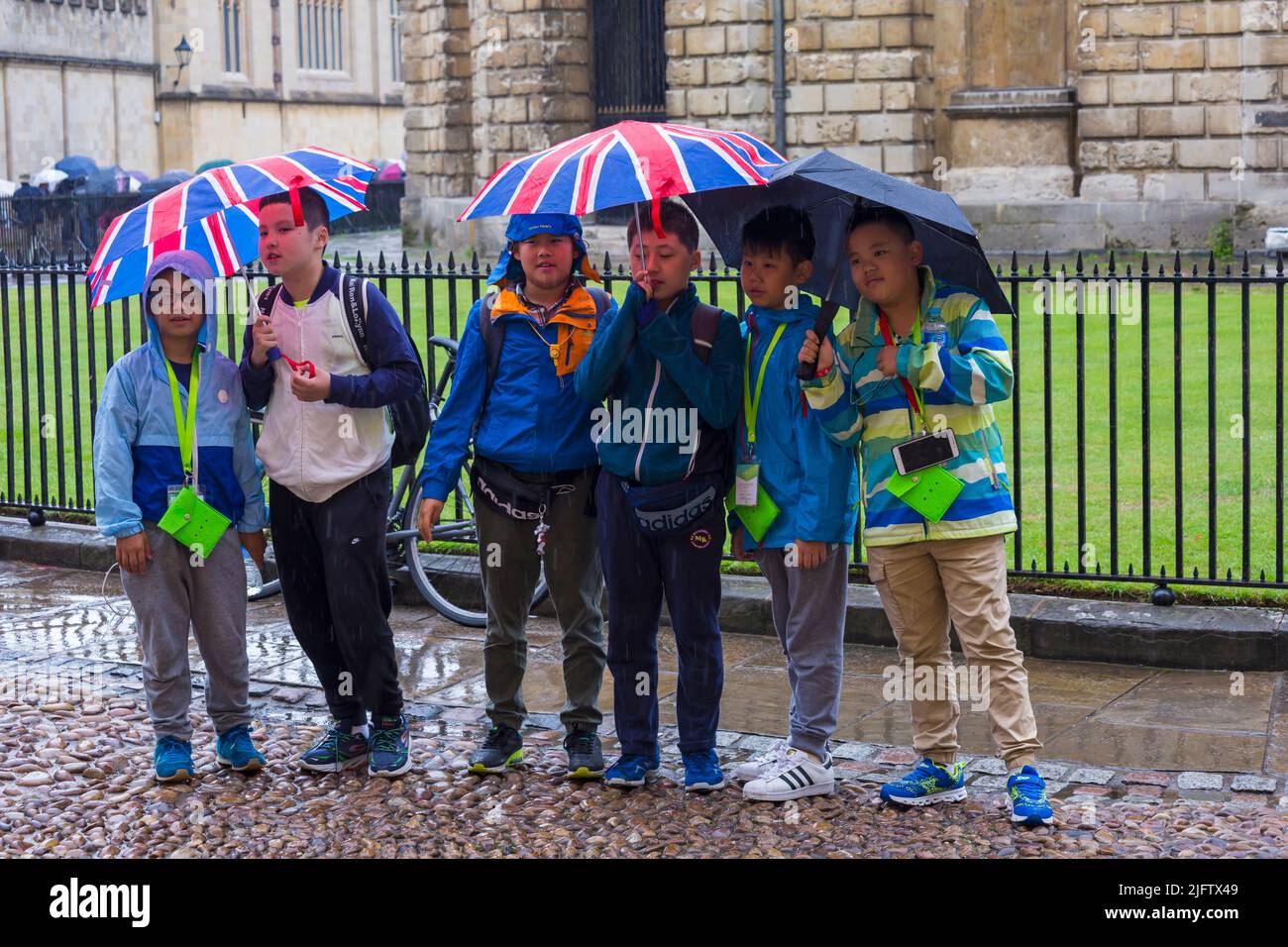 Boys sheltering under umbrellas in the pouring rain at Oxford ...