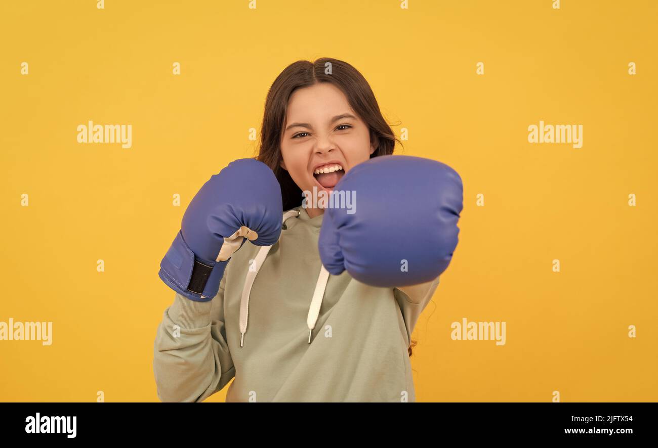 aggressive child punching in boxing gloves on yellow background, sport ...