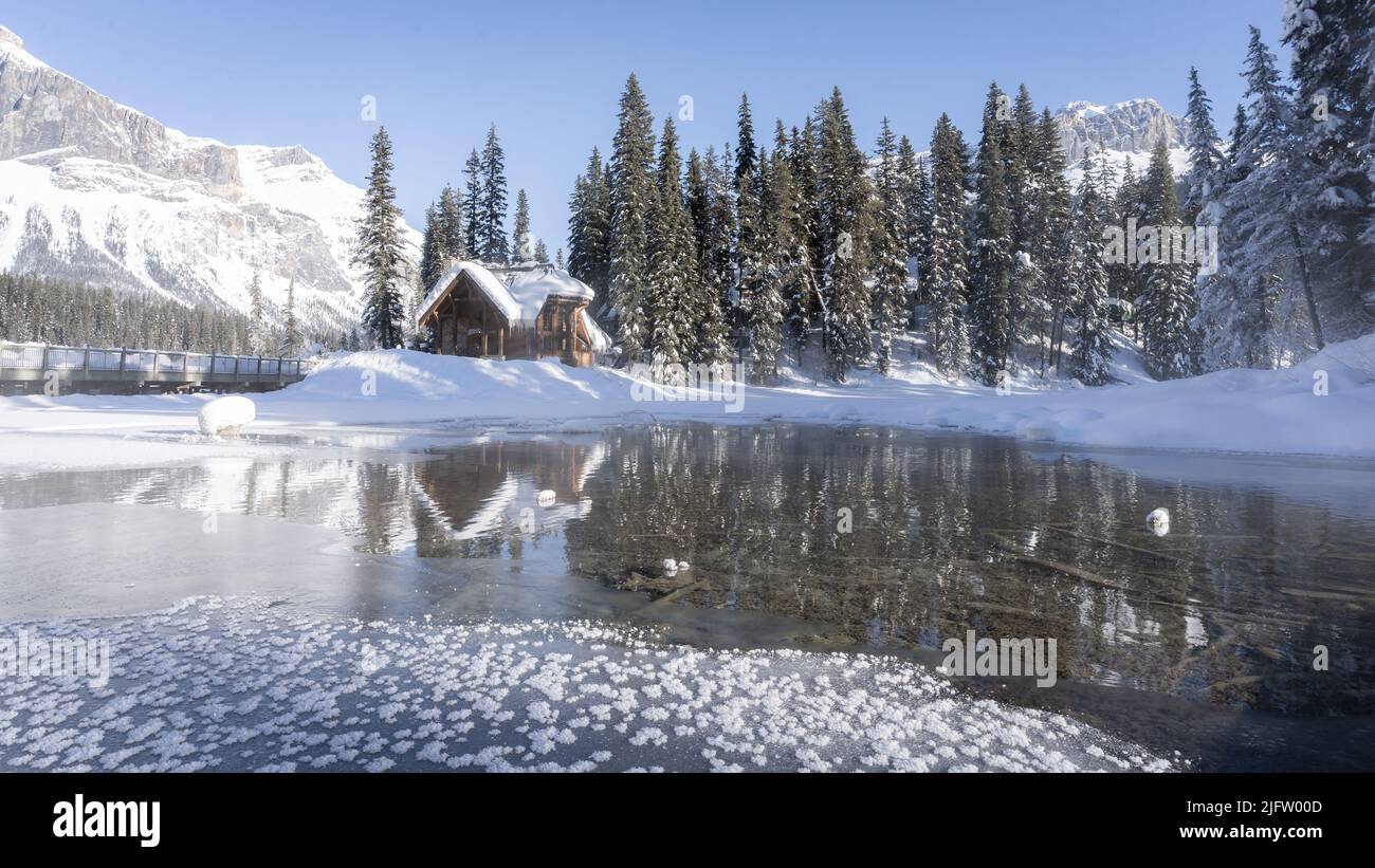 Small hut on the bank of frozen lake surrounded by mountains with and ...