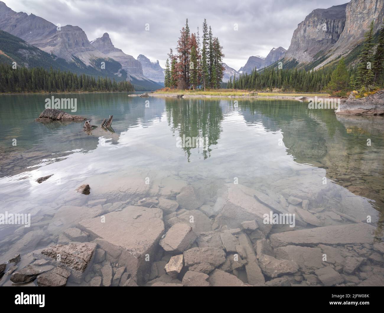 Island of trees in the middle of turquoise alpine lake surrounded by ...