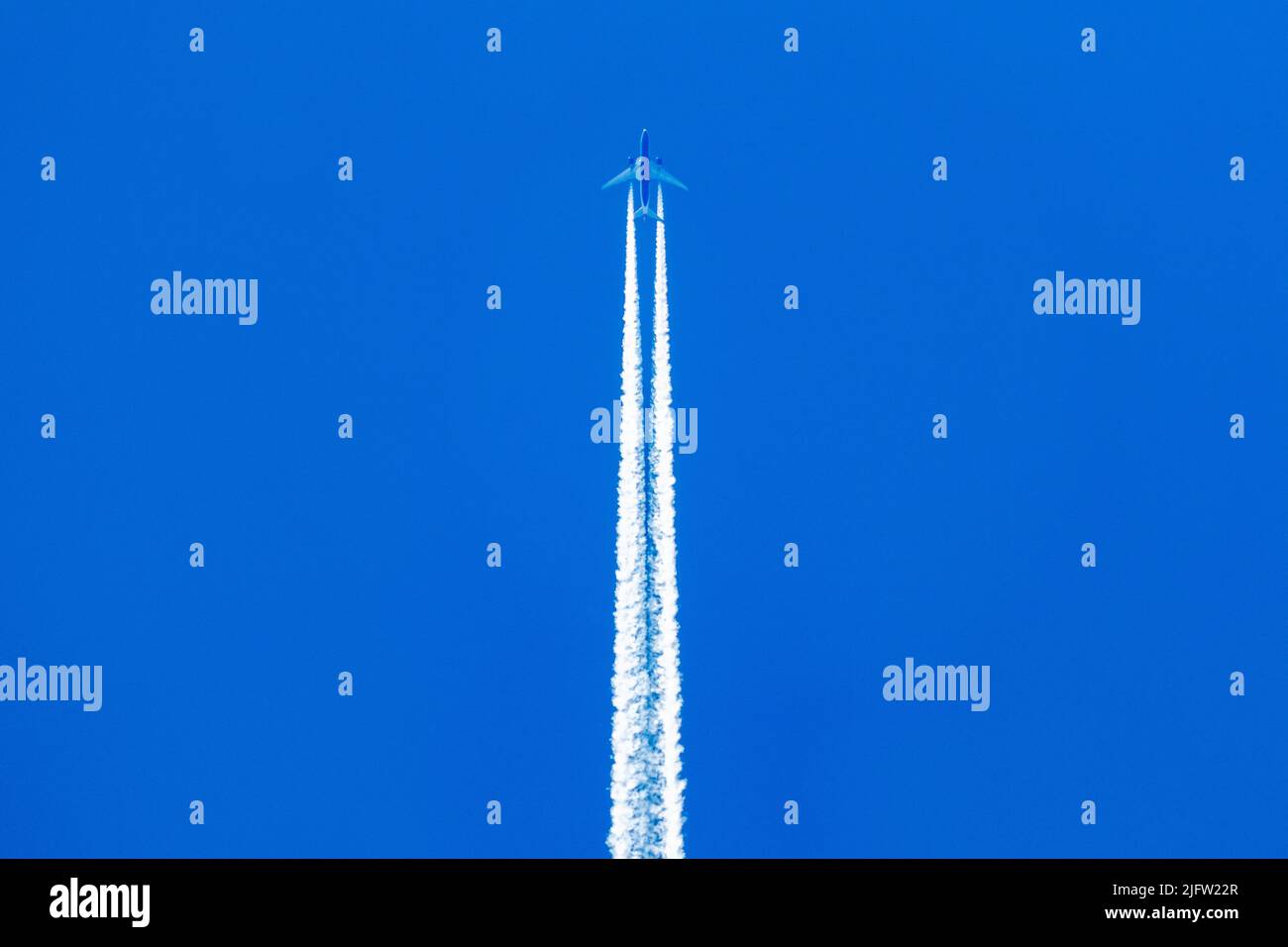 A low angle shot of long white trail of jet plane on blue sky Stock ...