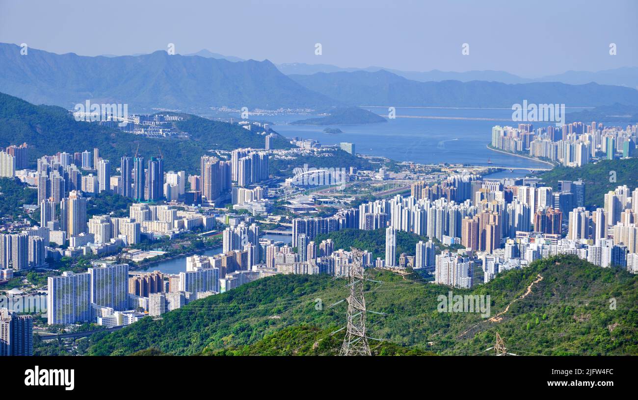 A bird's eye view of green hills against skyscrapers of Hing Kong on a ...