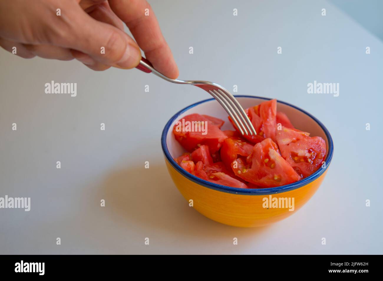 Hand stabbing a piece of chopped tomato with a fork Stock Photo - Alamy