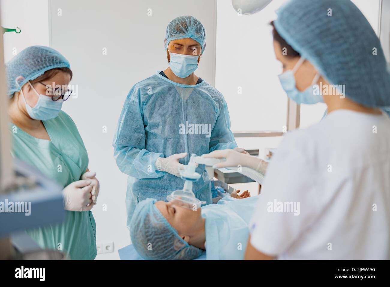 Doctor anesthesiologist holding breathing mask on patient face during ...