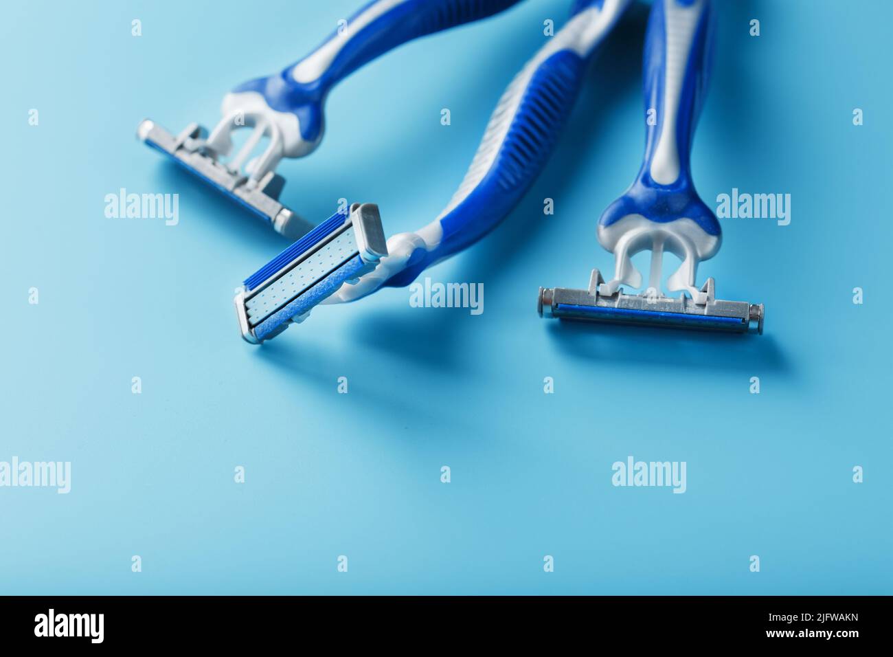 Three shaving machines on a blue background with free space, top view ...
