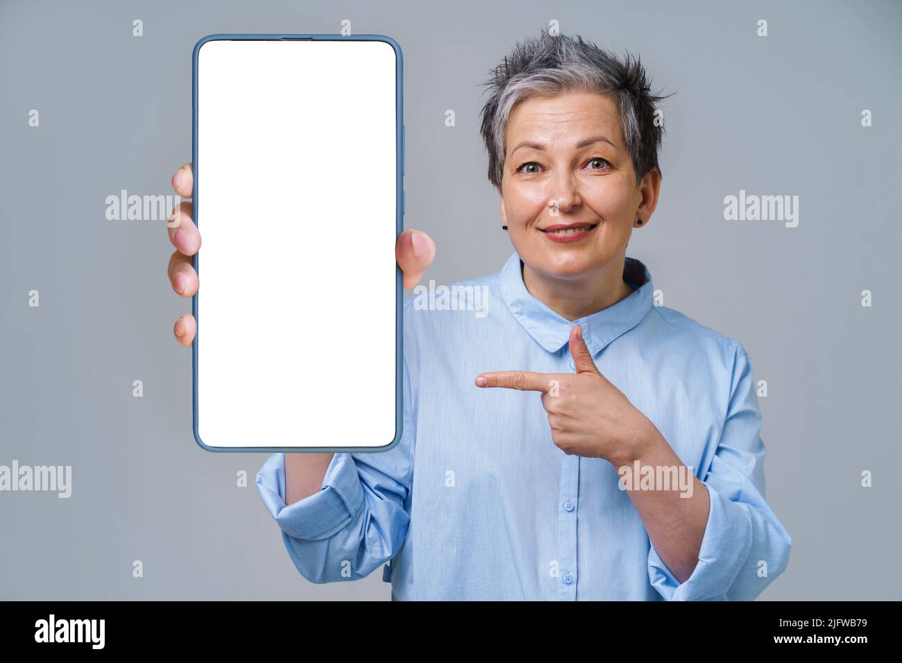 Mature silver, grey hair woman pointing at smartphone white screen ... Mature silver, grey hair woman pointing at smartphone white screen ...