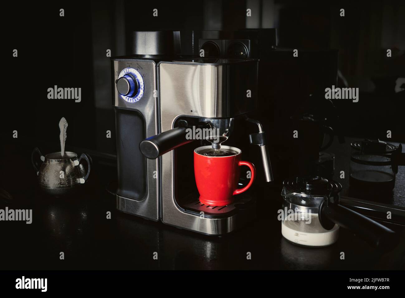 coffee maker and mug and milk on a black dark background . making ...