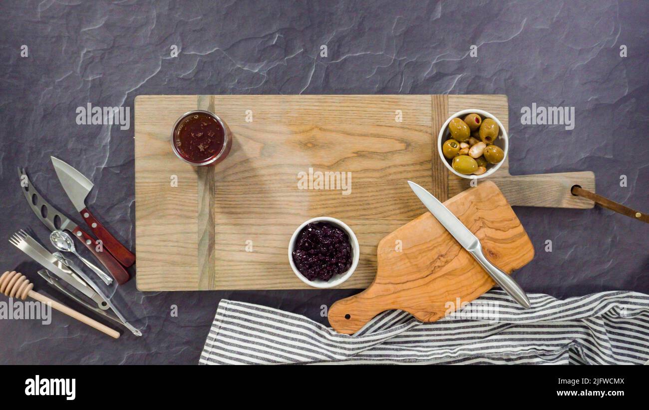 Flat lay. Arranging gourmet cheese, crakers, and fruits on a board for ...