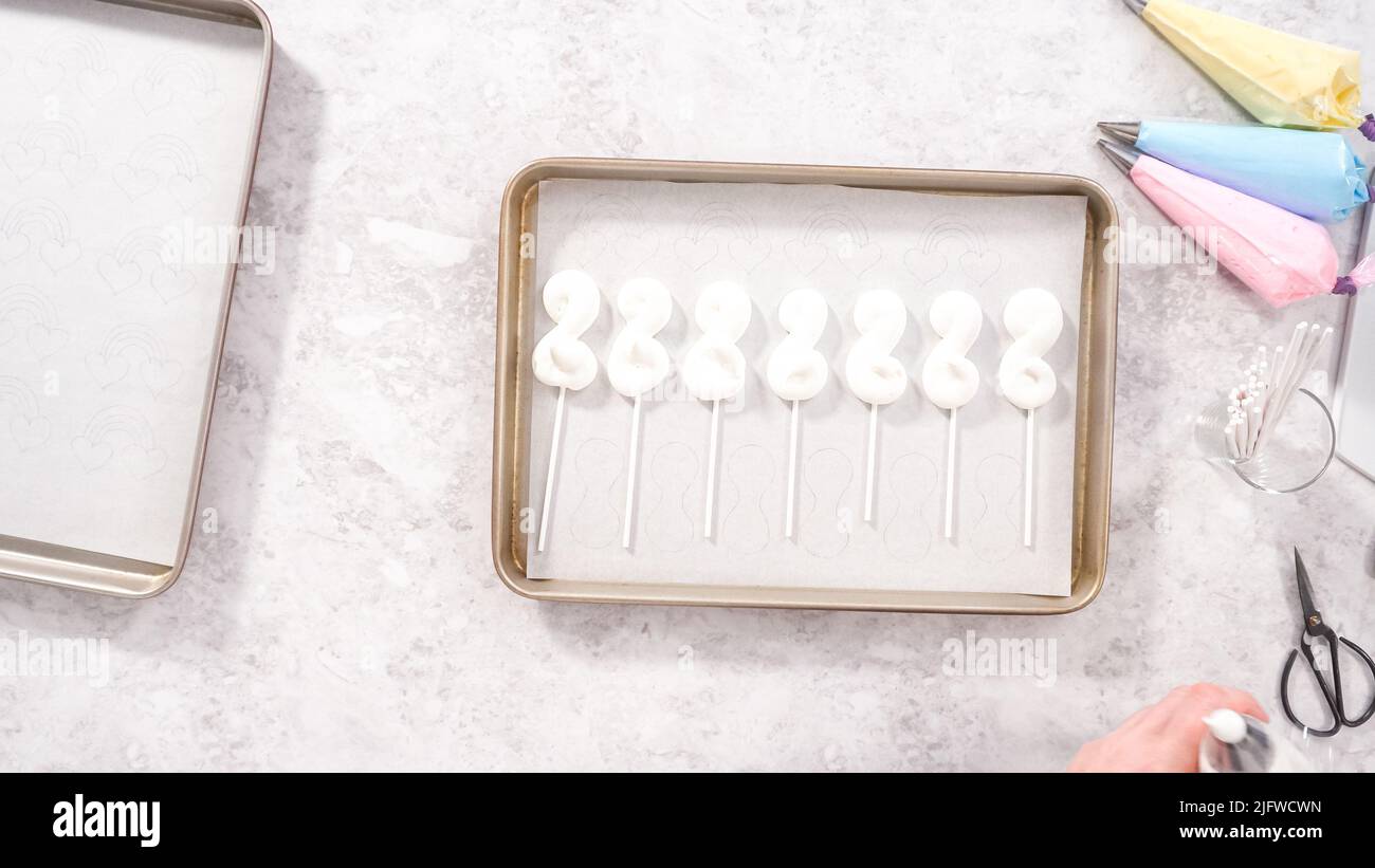 Flat lay. Step by step. Piping meringue mix into unicorn-shaped pops on ...