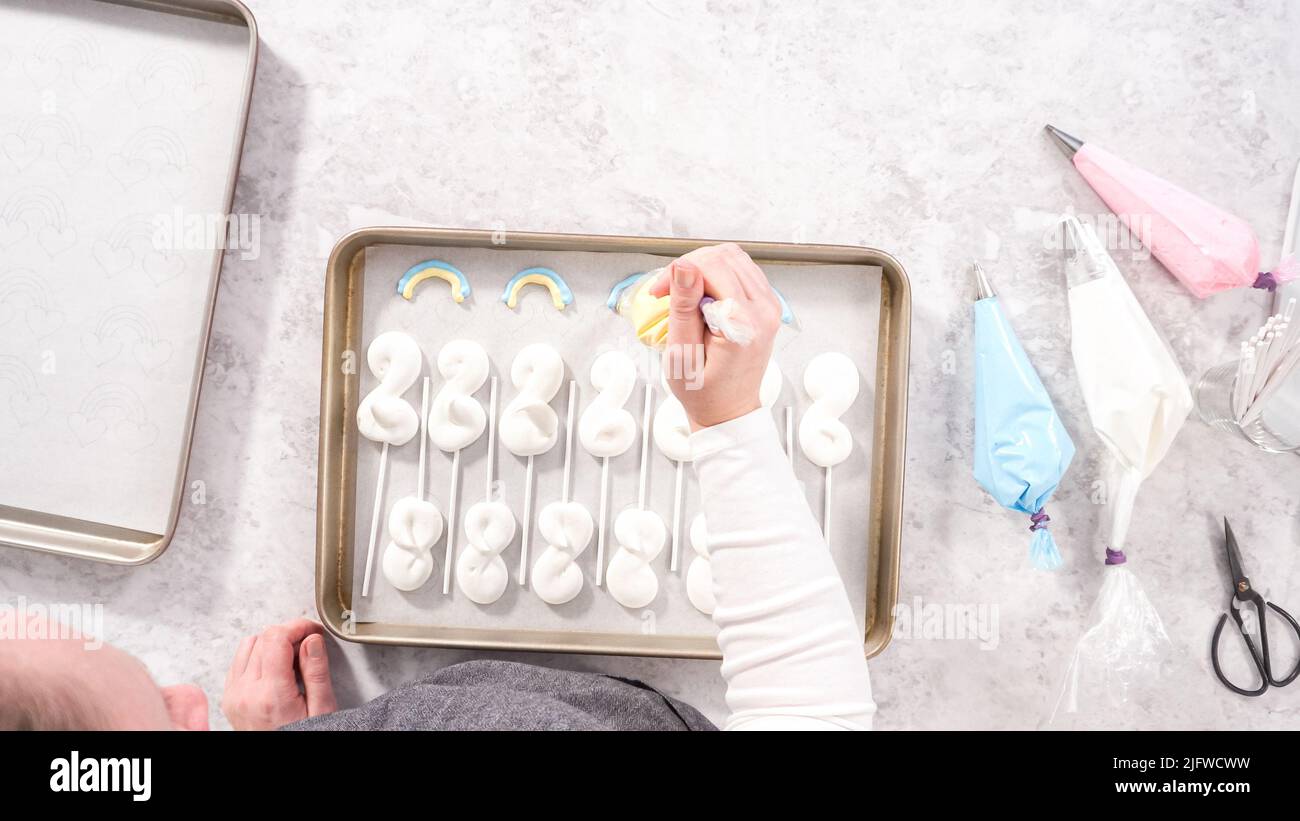 Flat lay. Step by step. Piping meringue mix into unicorn-shaped pops on ...