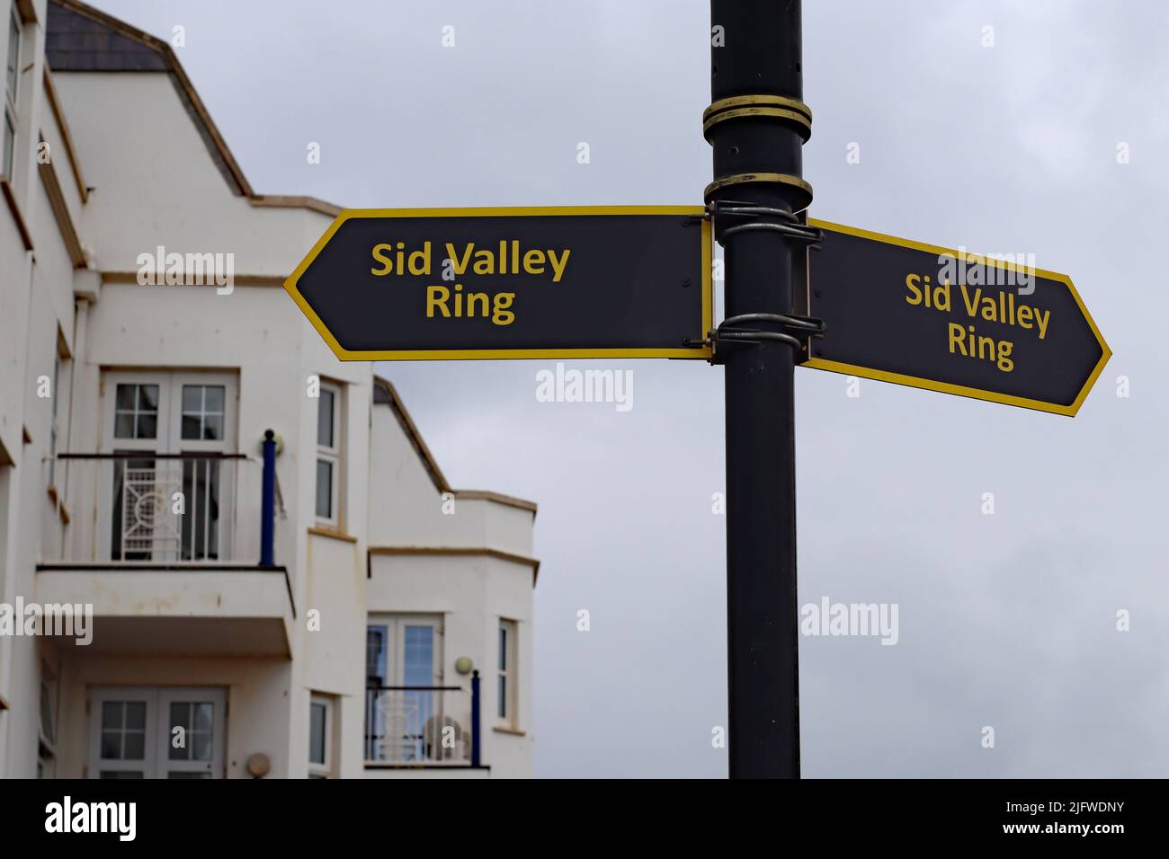 A sign with gold lettering on a black background in Sidmouth, Devon pointing out the route of ...
