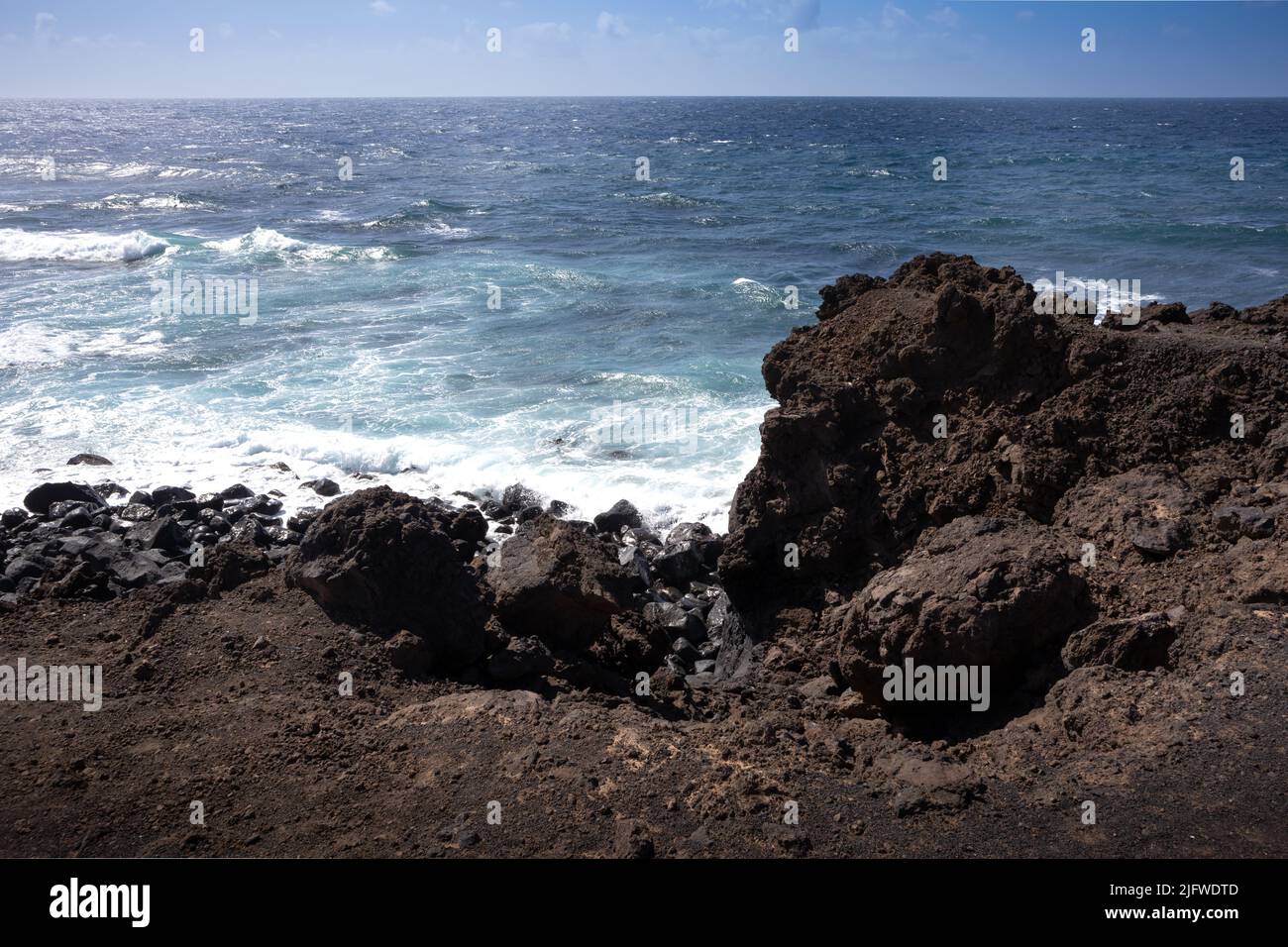 Rocks made of dark brown to black lava, creating the Atlantic ocean ...