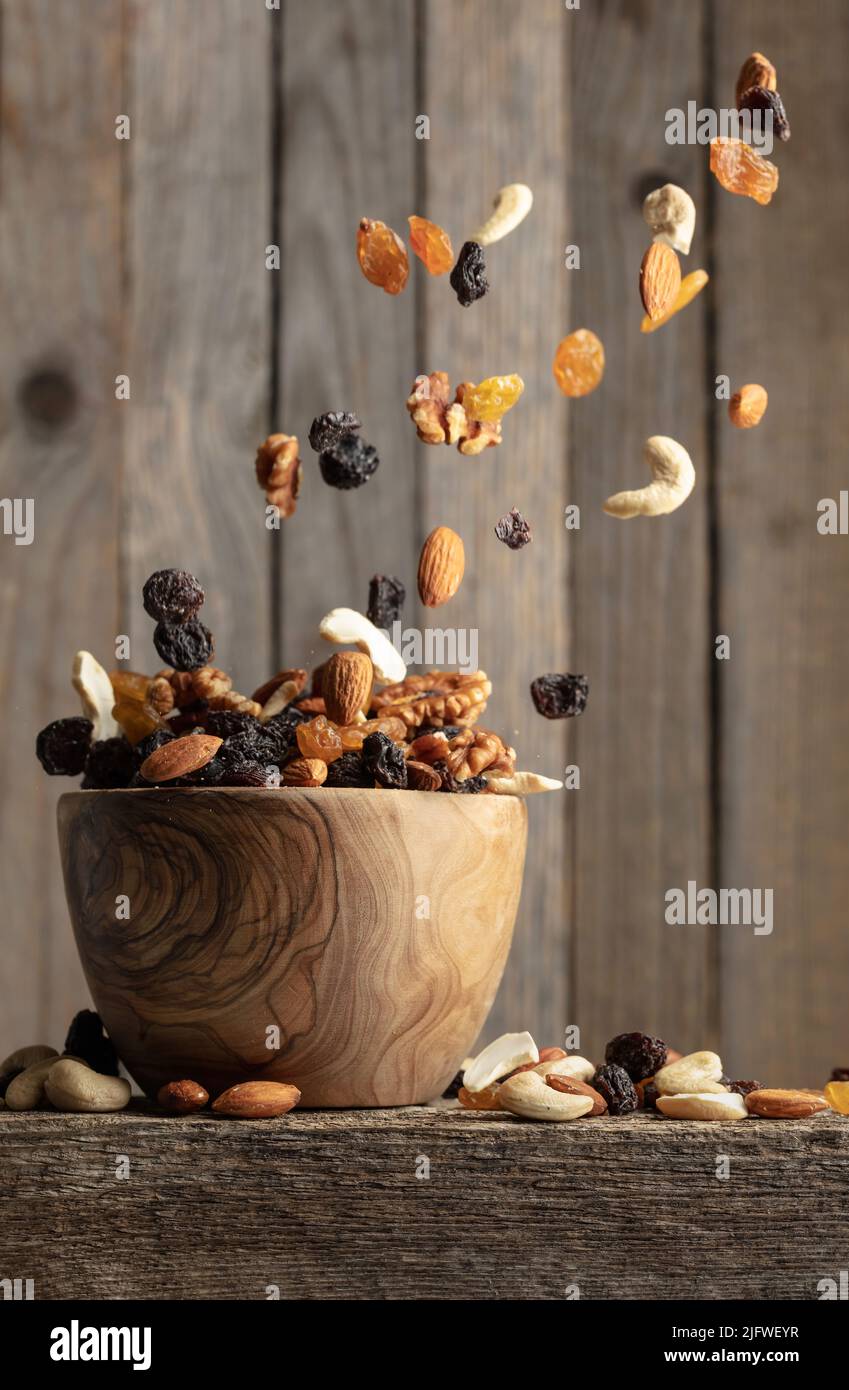 The mix of dried nuts and raisins on an old wooden table. Flying dried ...