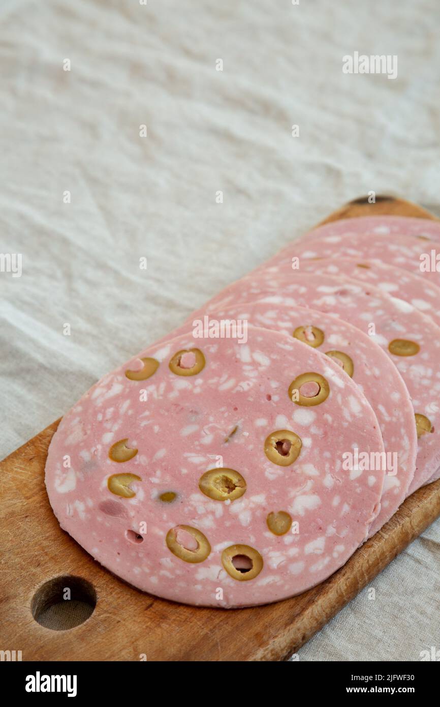 Organic Sliced Mortadella Sausage with Olives on a rustic wooden board ...