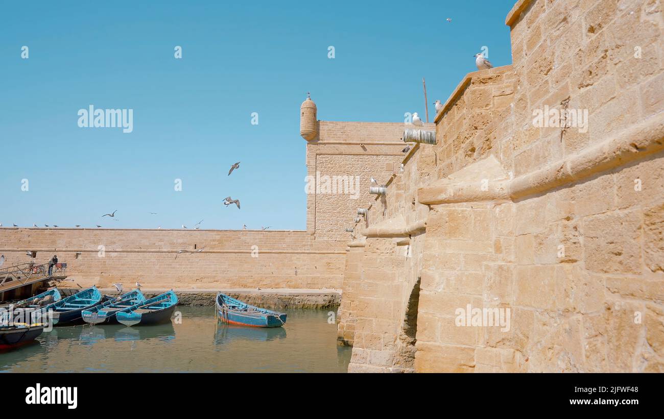 Old fortress and the calm sea with flying seagulls and moored boats ...