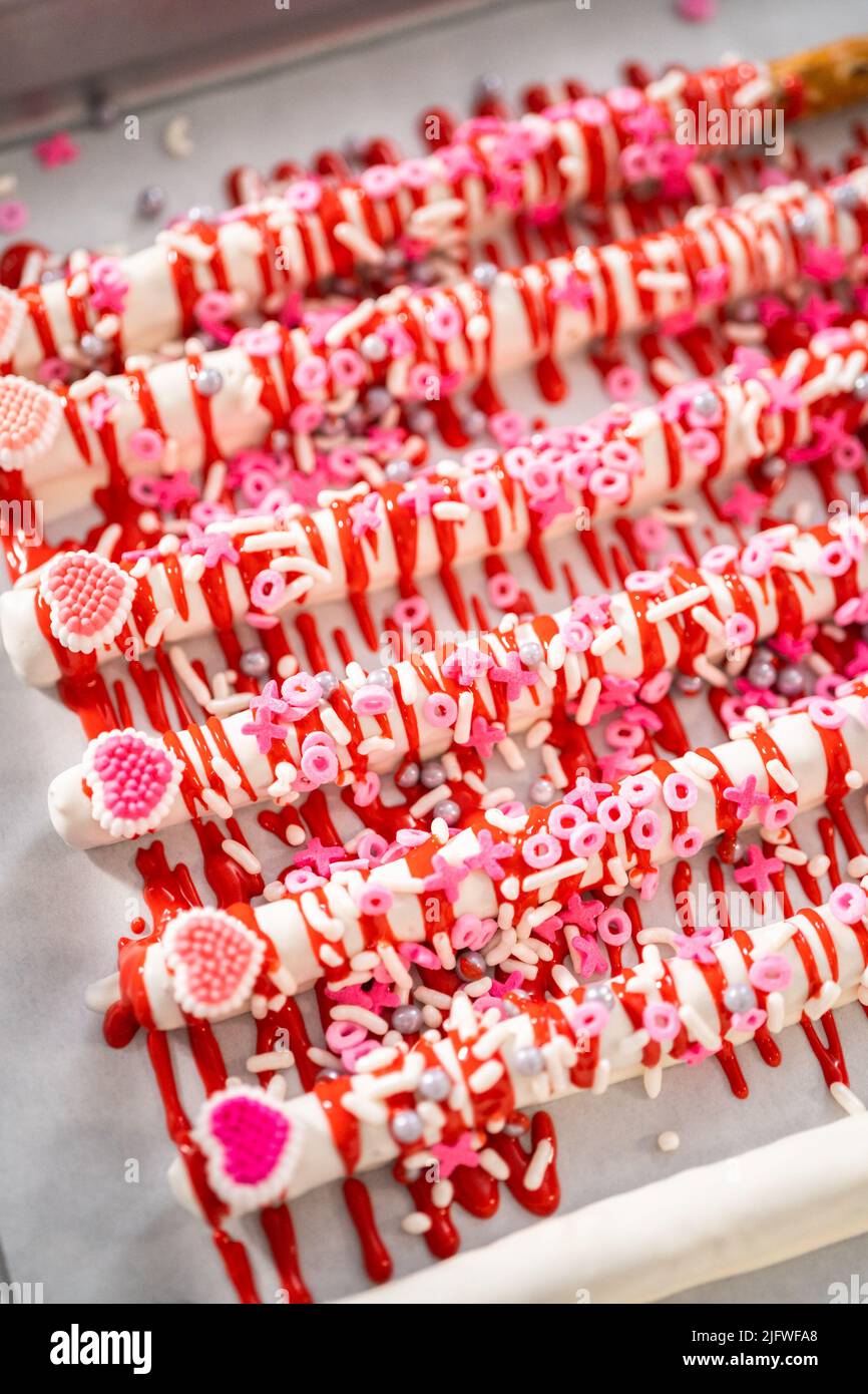 Drizzling melted chocolate over chocolate-dipped pretzels rods and ...