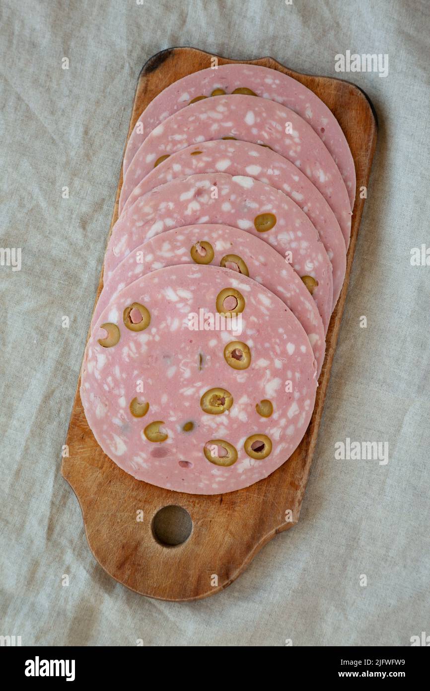 Organic Sliced Mortadella Sausage with Olives on a rustic wooden board ...