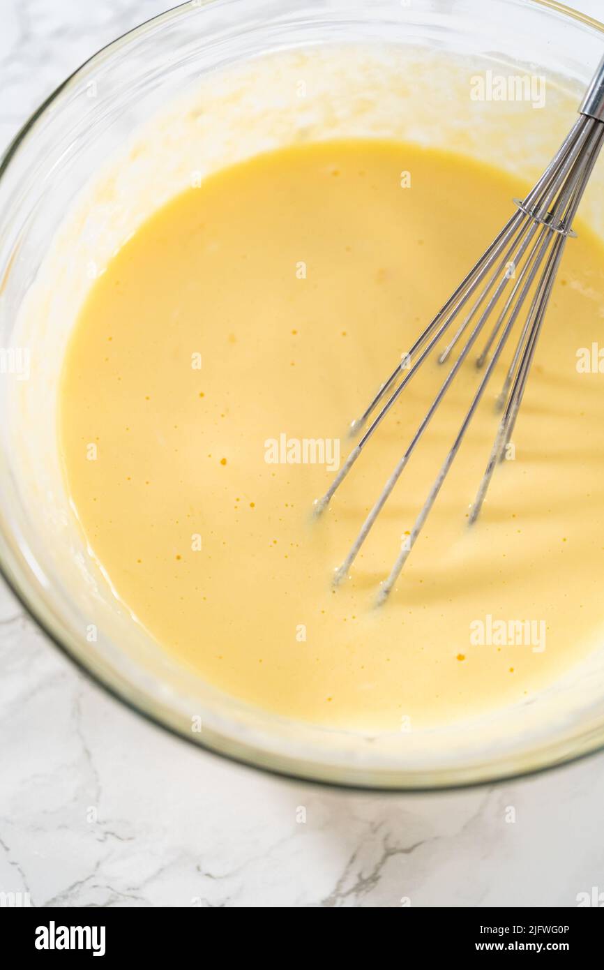 Mixing wet ingredients in a large glass mixing bowl to bake red velvet ...