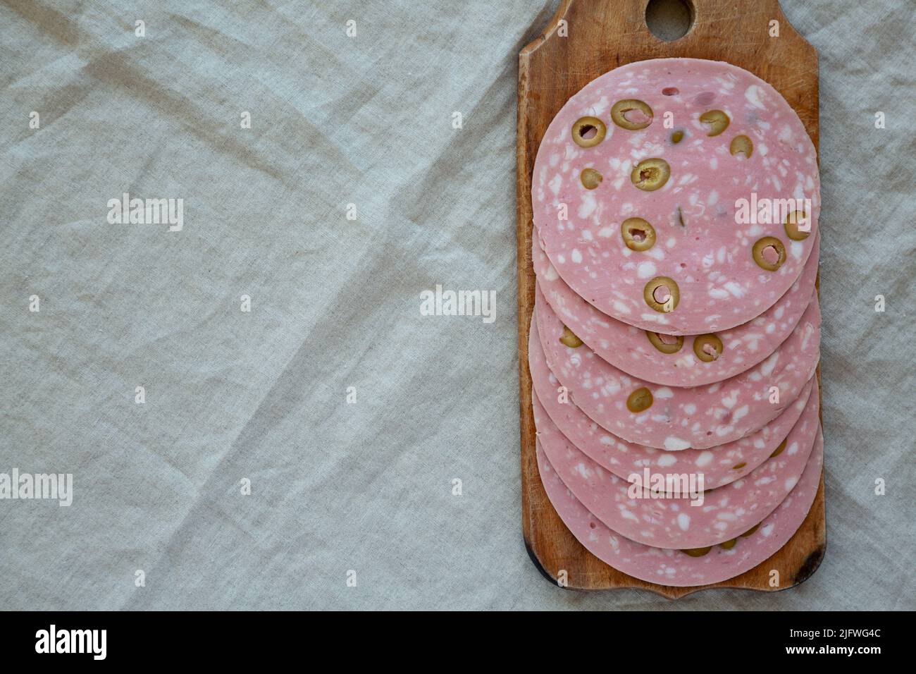 Organic Sliced Mortadella Sausage with Olives on a rustic wooden board ...