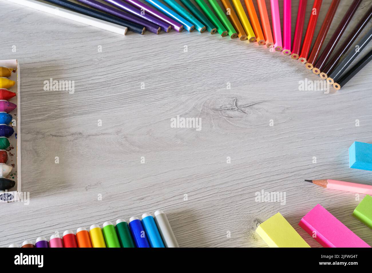 A table full of colored school pencils making a rainbow and supplies ...