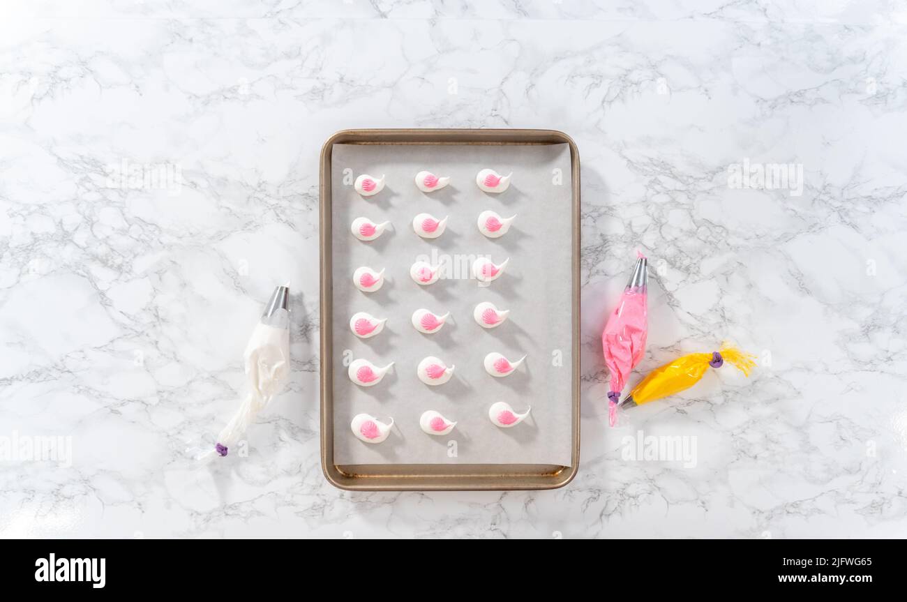 Piping meringue with piping bags into the baking sheet lined with ...