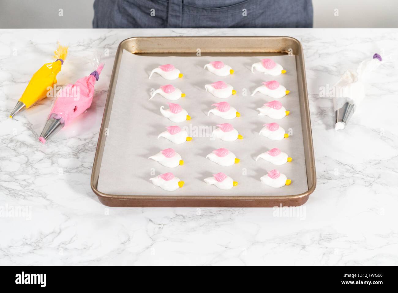 Piping meringue with piping bags into the baking sheet lined with ...