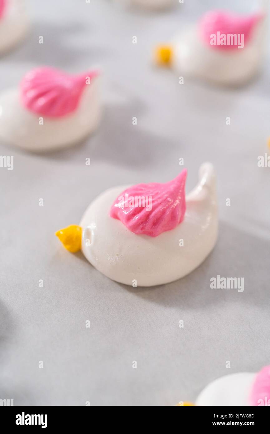 Piping meringue with piping bags into the baking sheet lined with ...