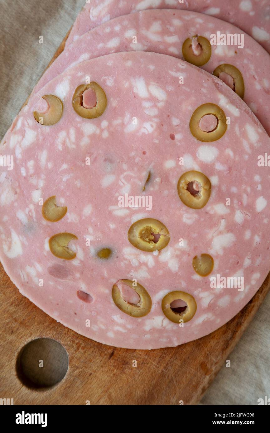 Organic Sliced Mortadella Sausage with Olives on a rustic wooden board ...