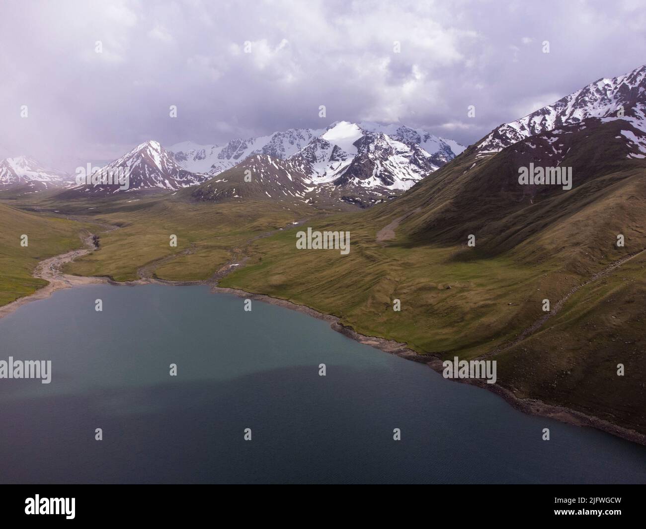 Aerial view of lake surrounded by snow capped peaks in the Tian Shan ...