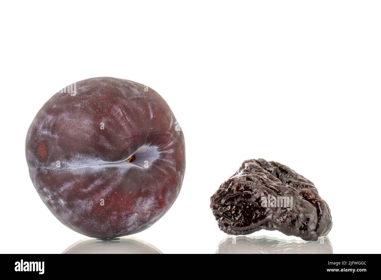 One ripe fresh black plum and one prunes, close-up, isolated on a white ...