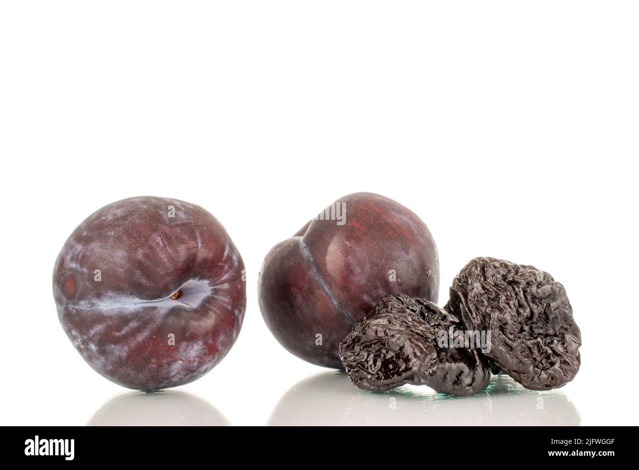 Two ripe fresh black plums and two prunes, close-up, isolated on a ...