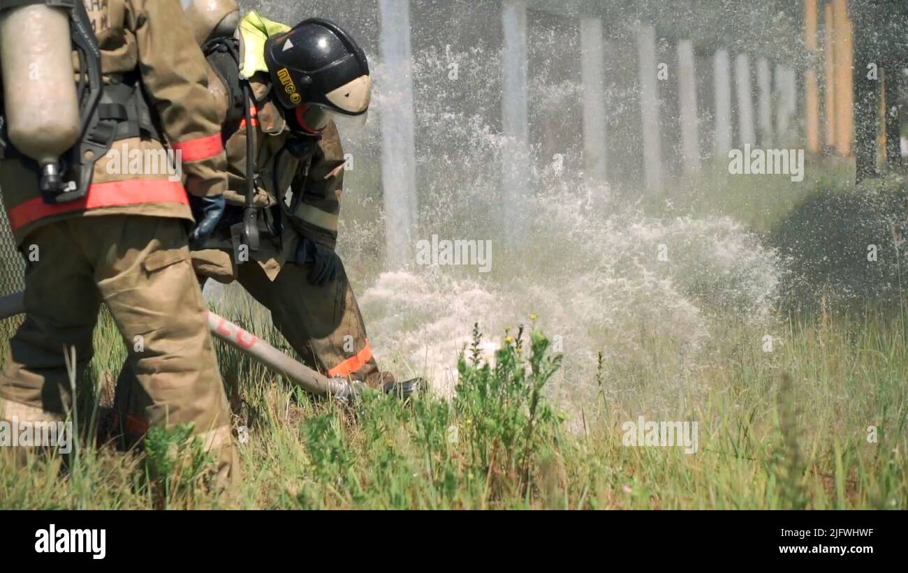 Firefighters. Clip. Two masked men who conduct exercises with a hose ...