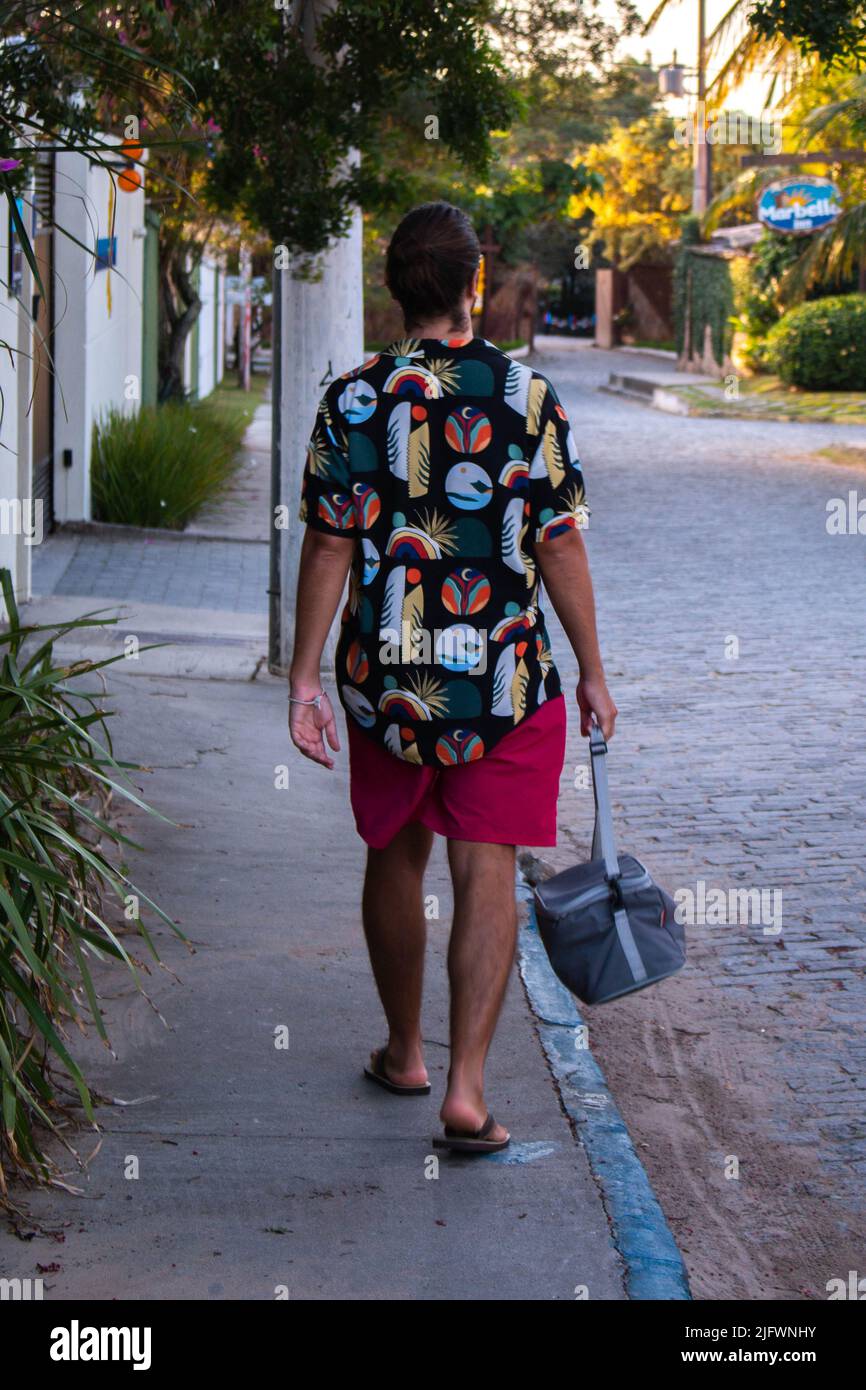 Young man walking backwards in the city of Buzios, Brazil. Wearing ...