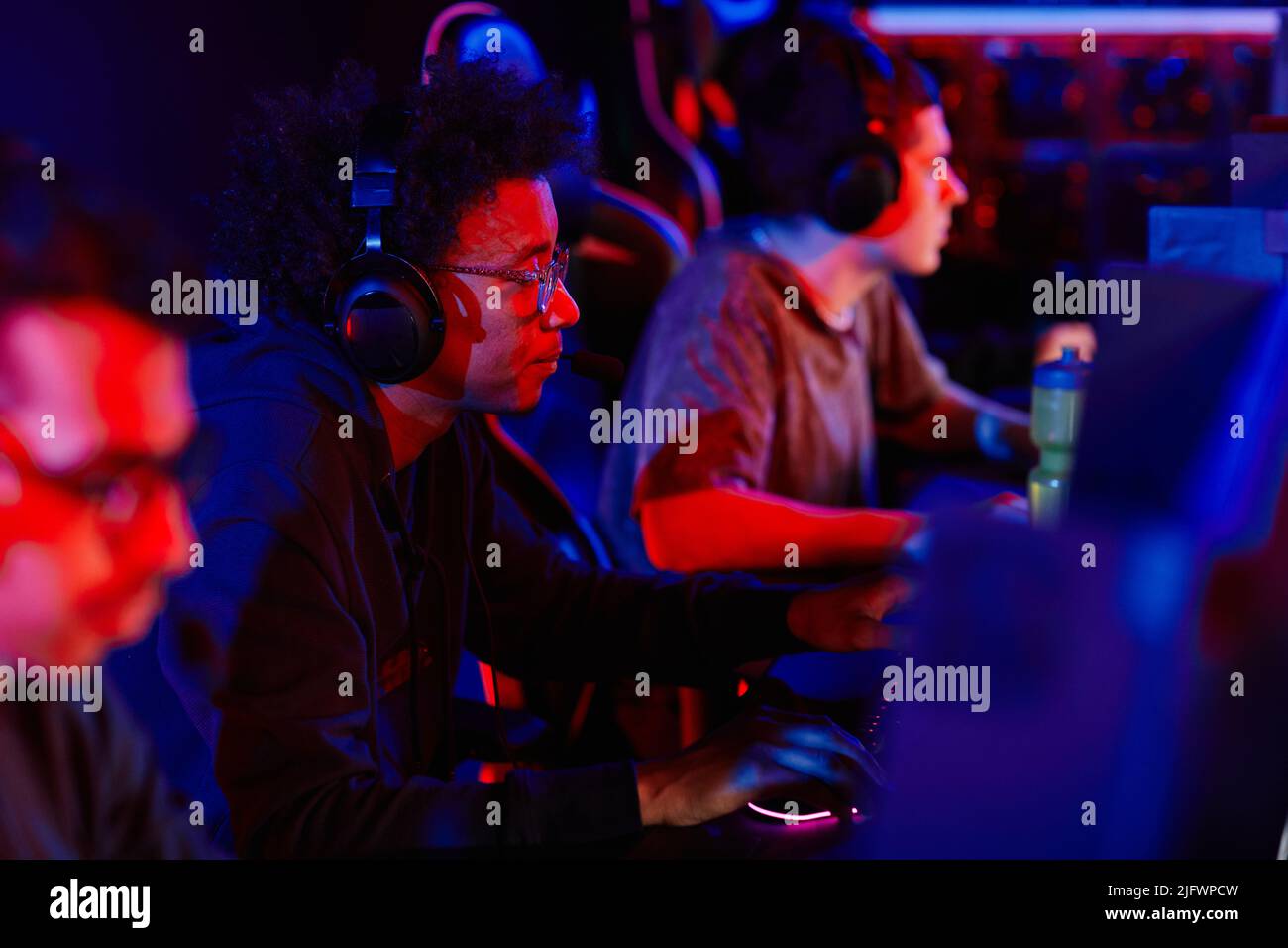 Side view portrait of young black man playing video games with diverse ...