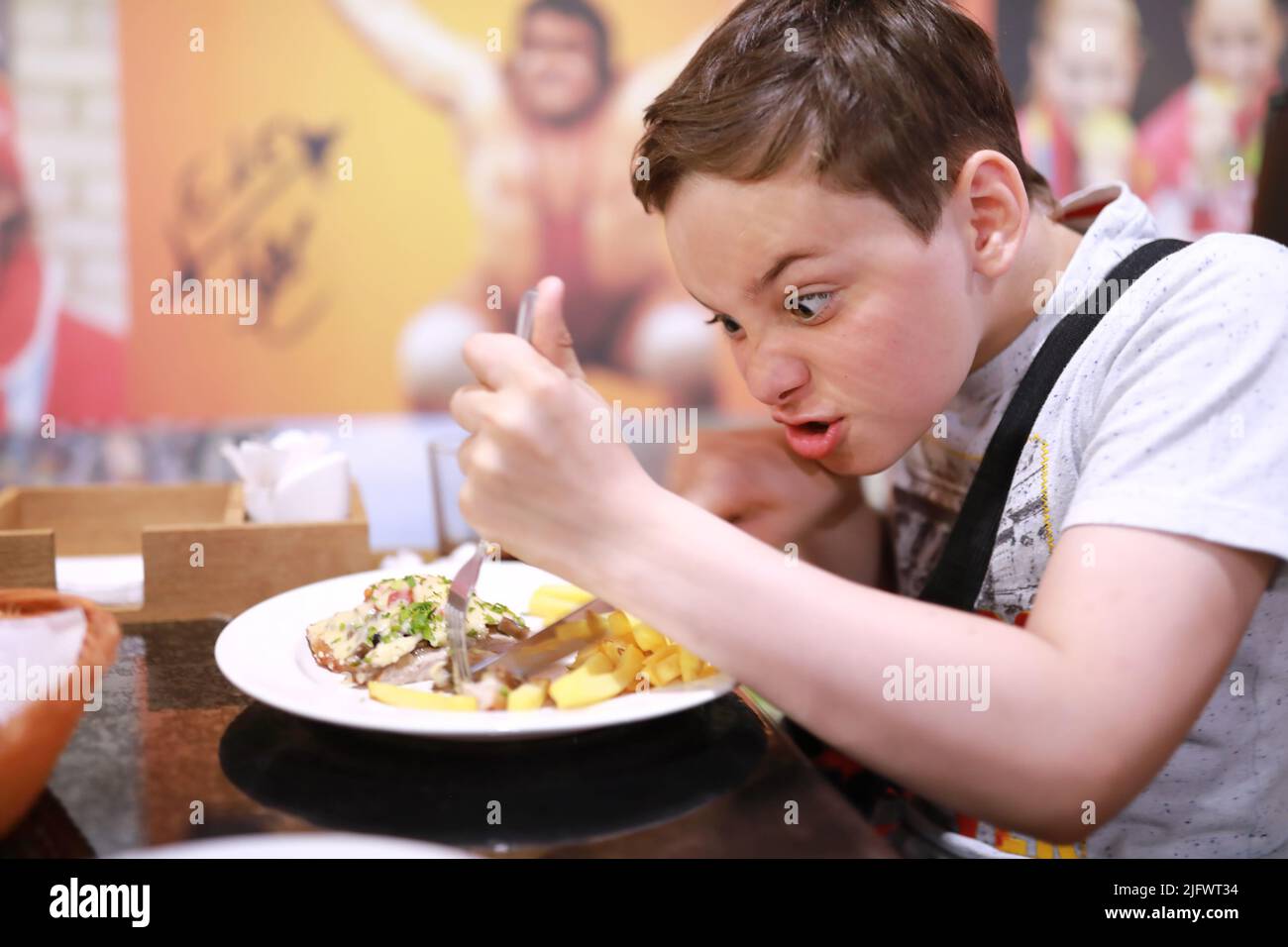 Hungry child cutting baked meat in restaurant Stock Photo - Alamy