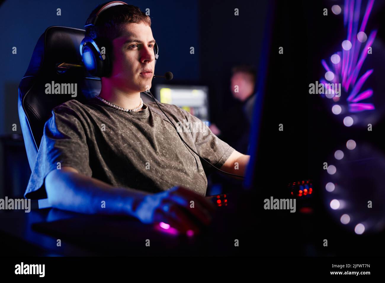 Side view portrait of Caucasian young man playing video games in dark ...